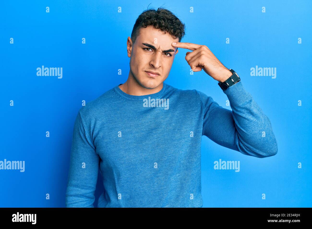 Hispanic young man wearing casual winter sweater pointing unhappy to ...