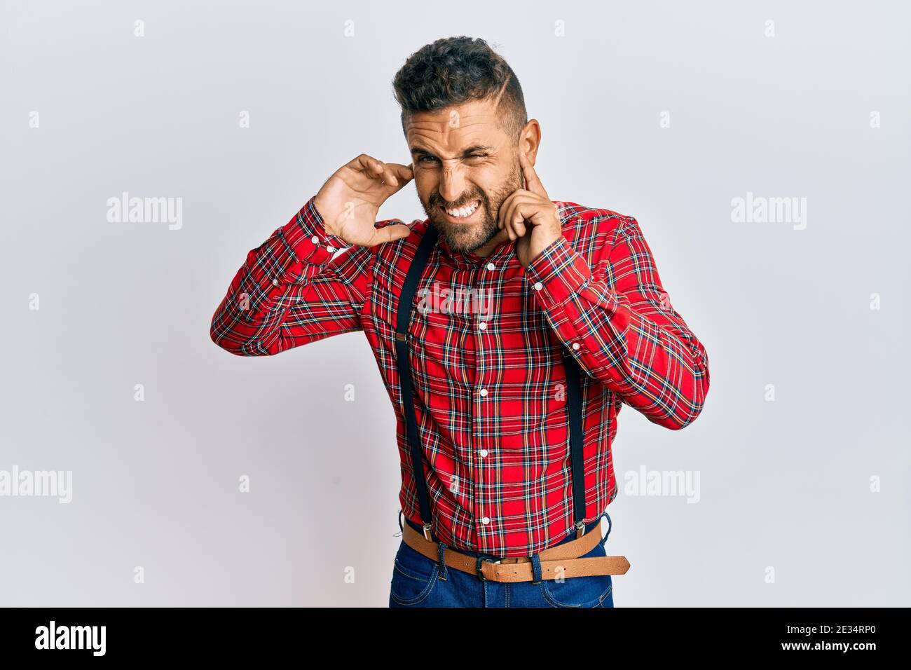 Handsome man with beard wearing hipster elegant look covering ears with ...