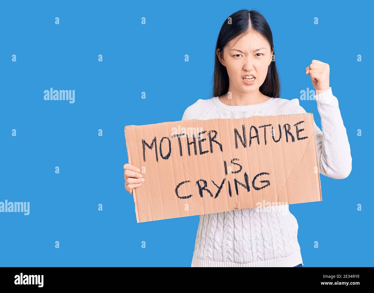 Young beautiful chinese woman holding mother nature is crying cardboard ...