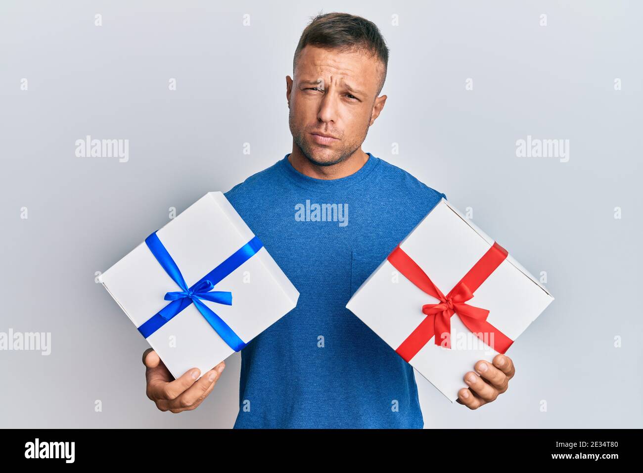 Handsome muscle man holding gifts depressed and worry for distress ...