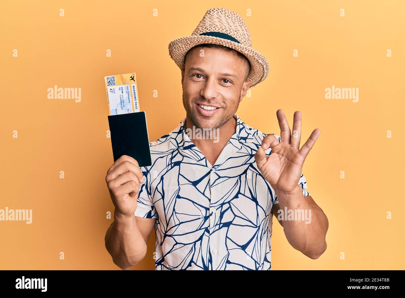 Handsome muscle man holding boarding pass and passport doing ok sign ...