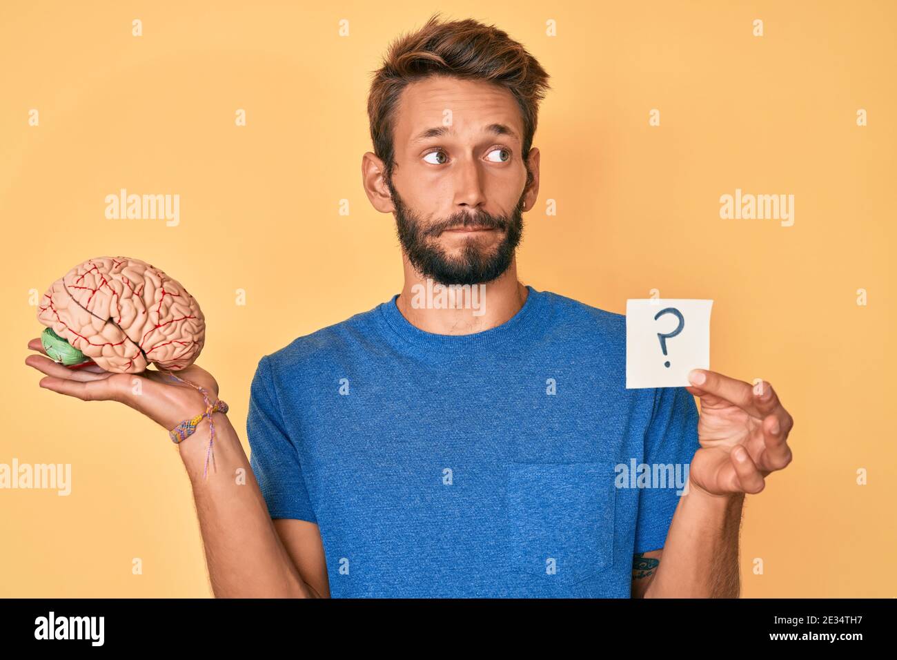 Handsome caucasian man with beard holding brain and question mark ...