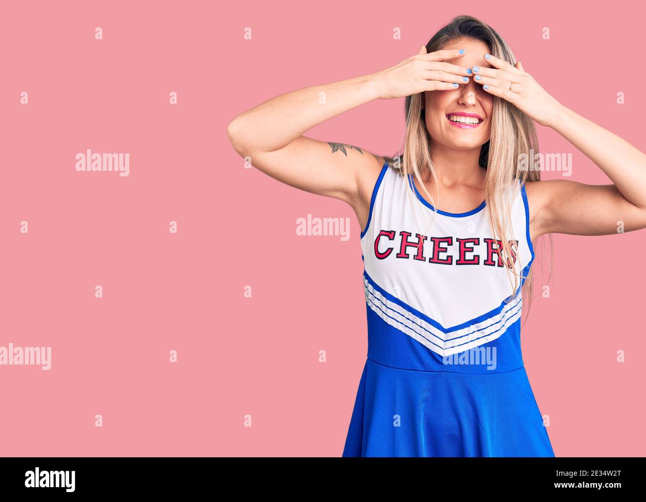 Young Beautiful Blonde Woman Wearing Cheerleader Uniform Covering Eyes