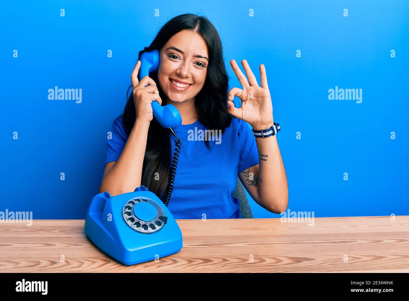 Beautiful brunette young woman speaking on vintage telephone doing ok ...