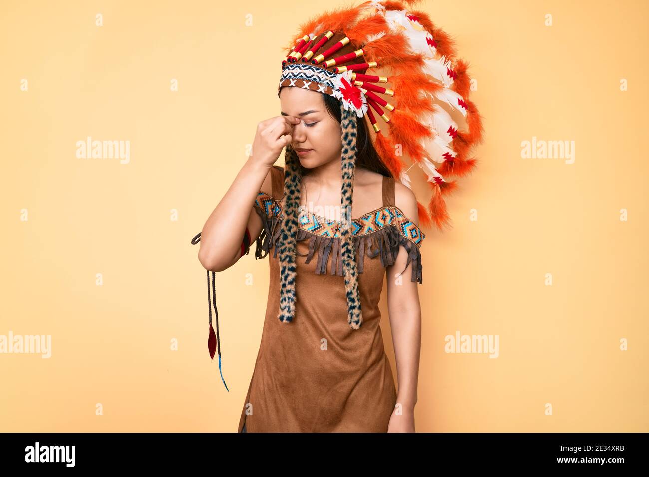 Young beautiful latin girl wearing indian costume tired rubbing nose ...