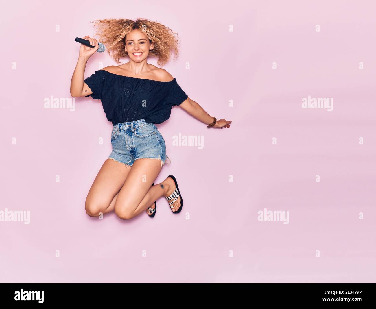 Young beautiful curly singer girl smiling happy singing song using ...