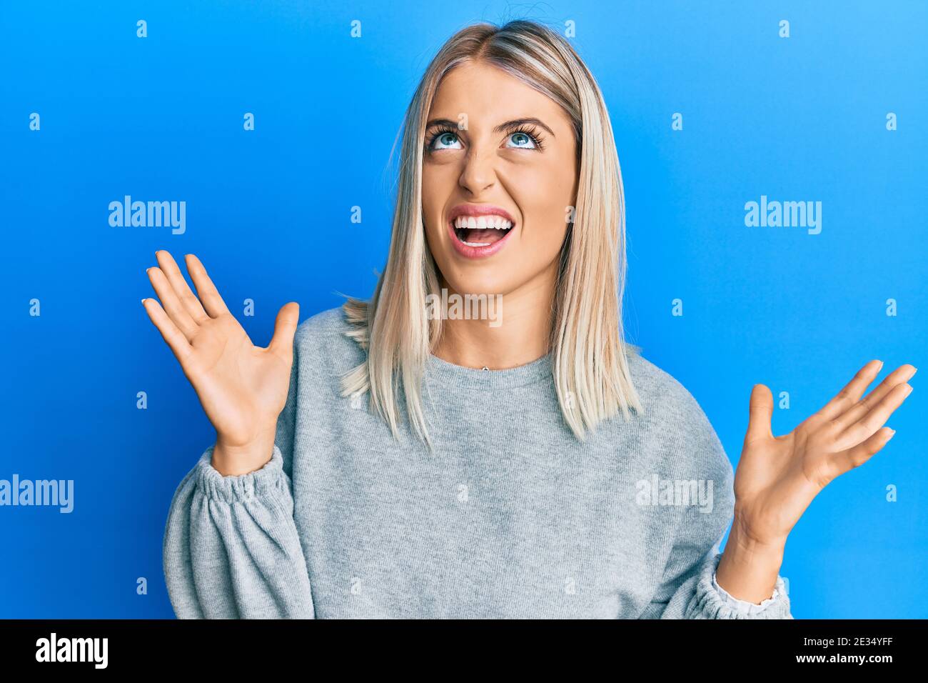 Beautiful blonde woman wearing casual clothes crazy and mad shouting ...