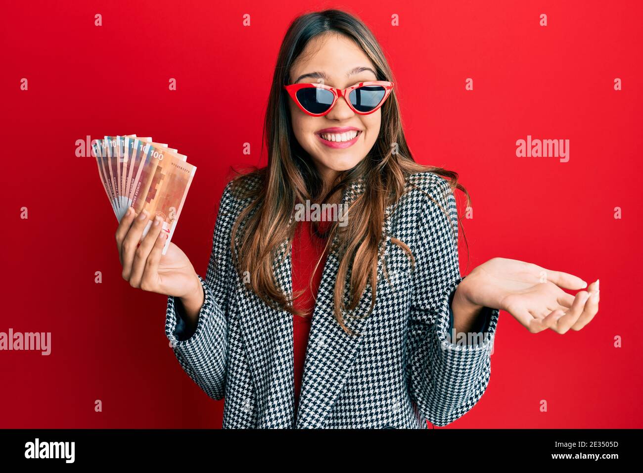 Young brunette woman holding 100 norwegian krone banknotes celebrating ...