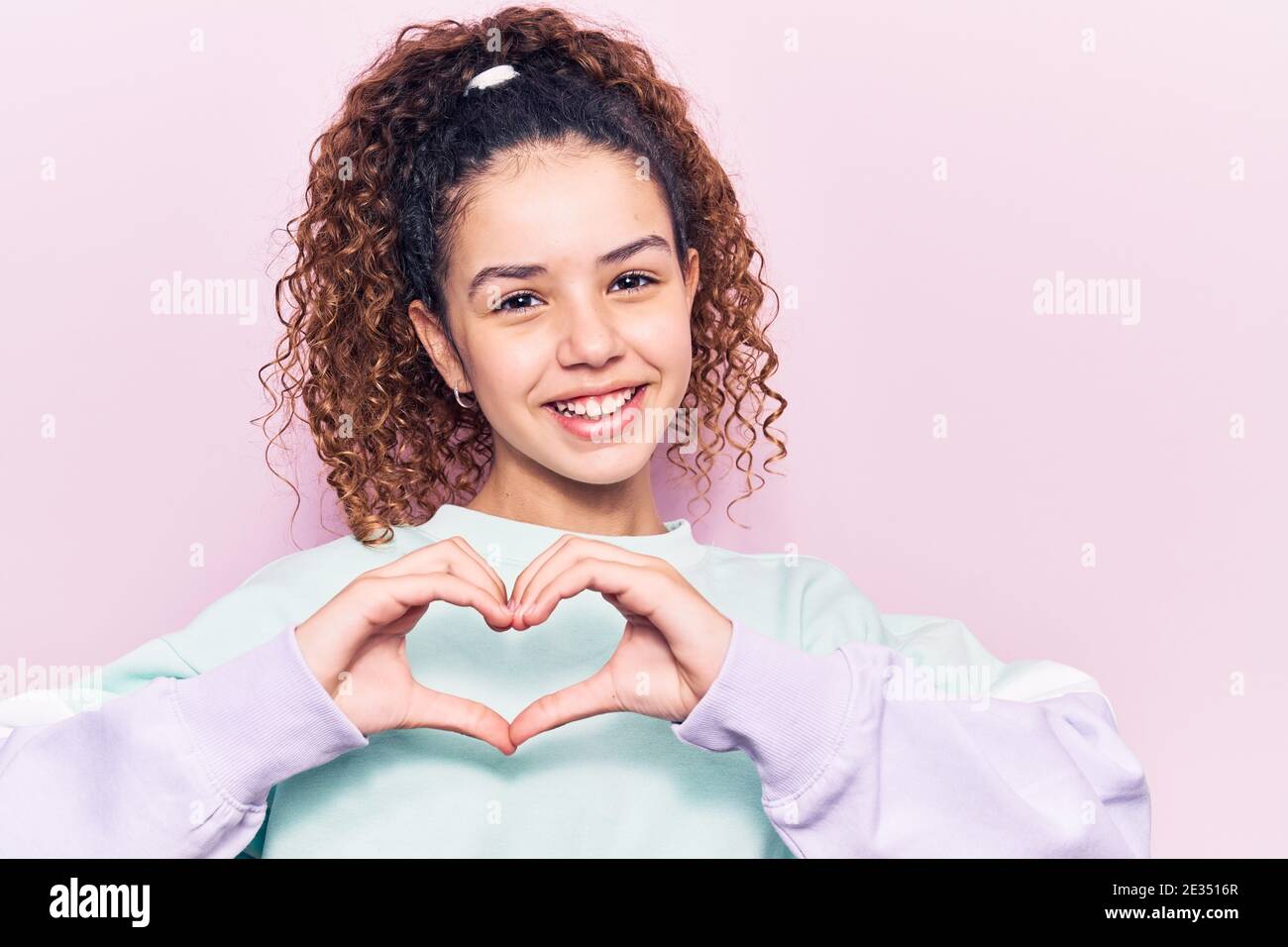 Beautiful kid girl with curly hair wearing casual clothes smiling in ...