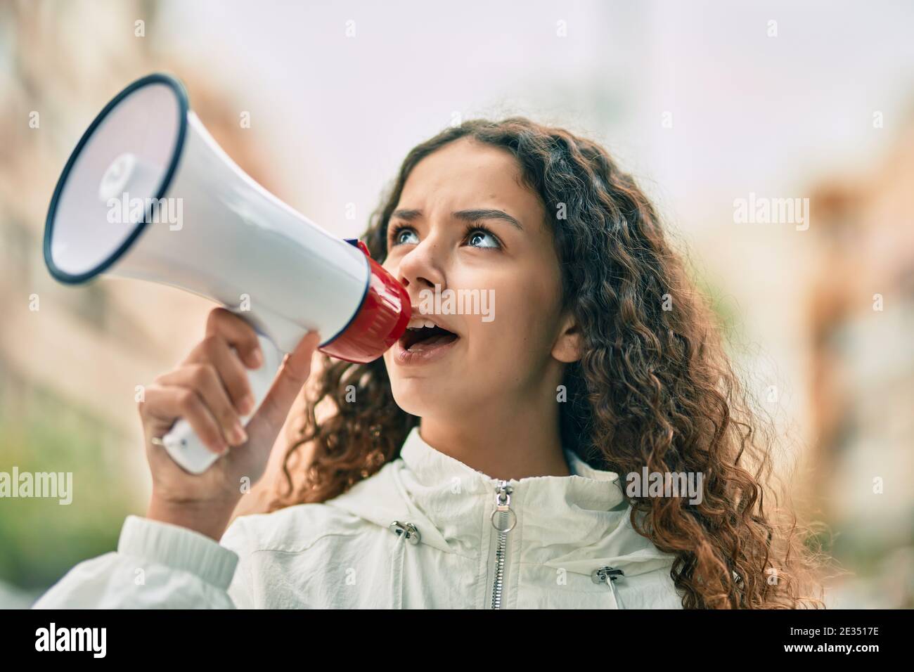Hispanic child girl shouting angry using megaphone at the city Stock ...