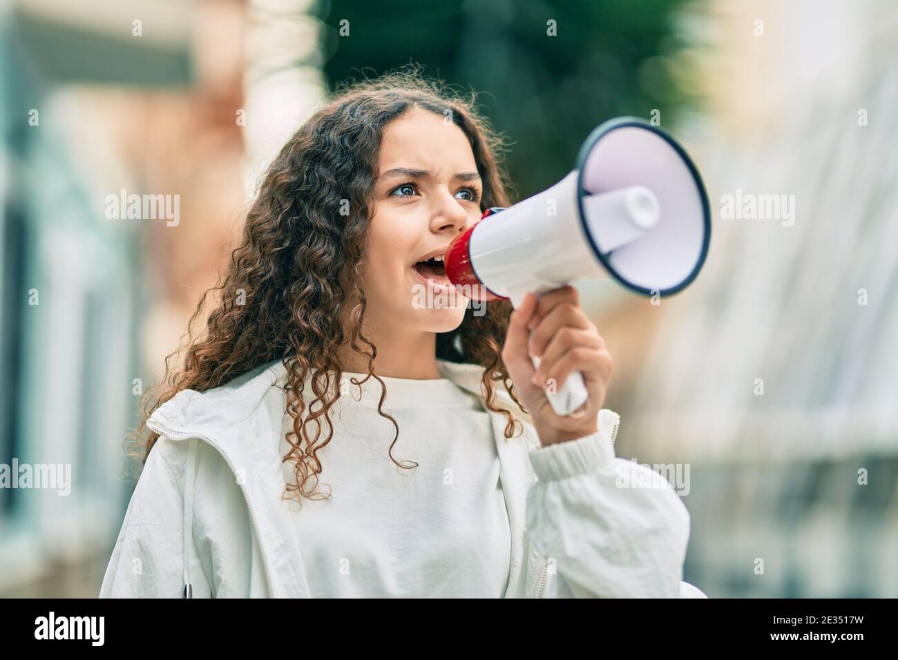 Hispanic child girl shouting angry using megaphone at the city Stock ...