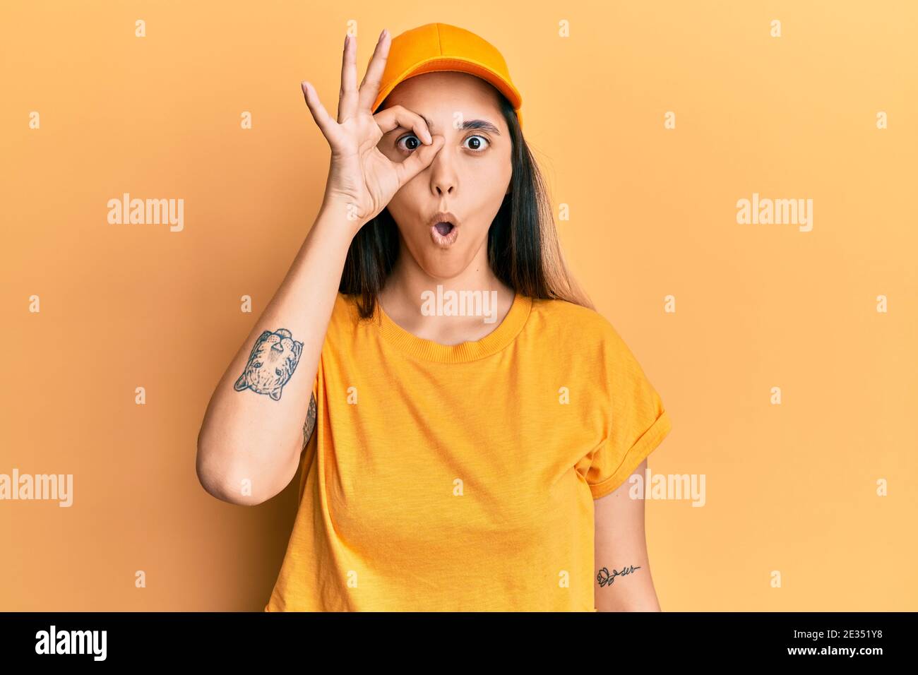 Young hispanic woman wearing delivery uniform and cap doing ok gesture ...
