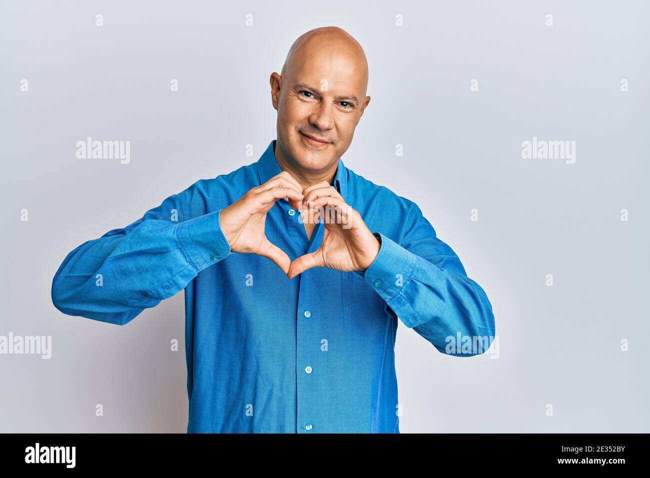 Middle age bald man wearing casual clothes smiling in love doing heart ...
