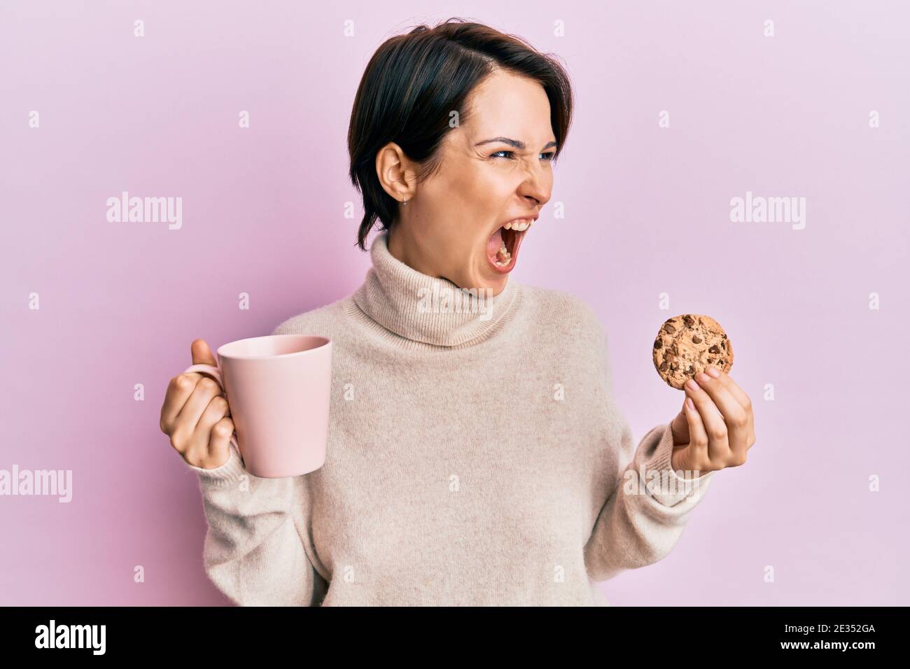 Young brunette woman with short hair drinking a cup of coffee and ...