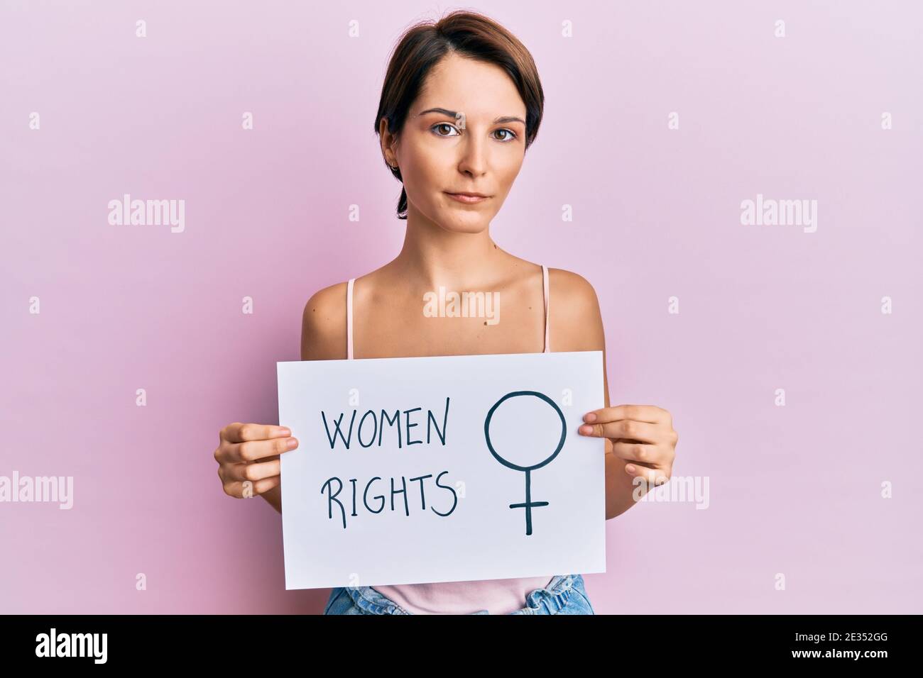 Young brunette woman with short hair holding woman rights banner ...