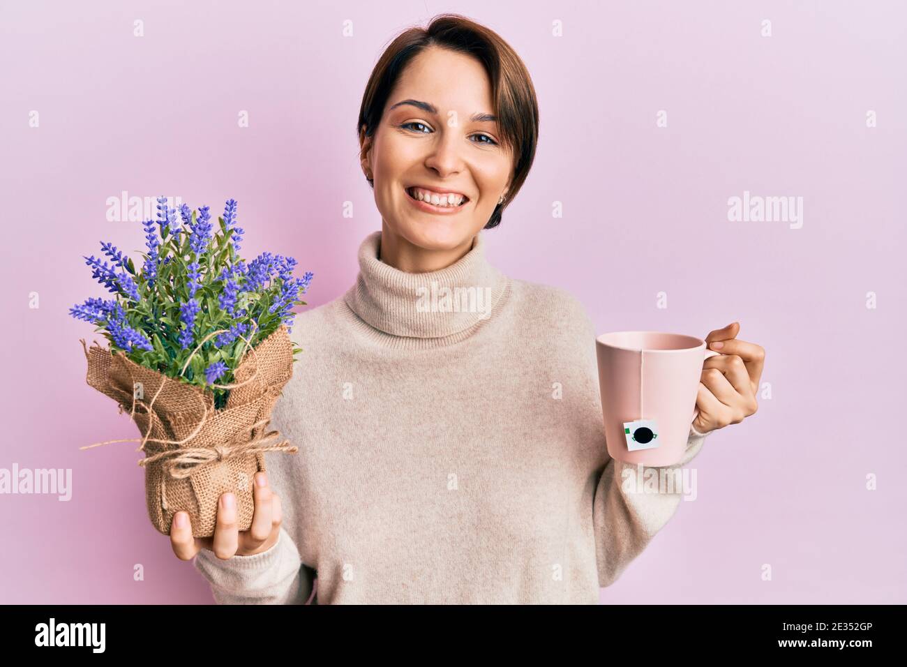 Young brunette woman with short hair drinking a cup of infused lavender ...
