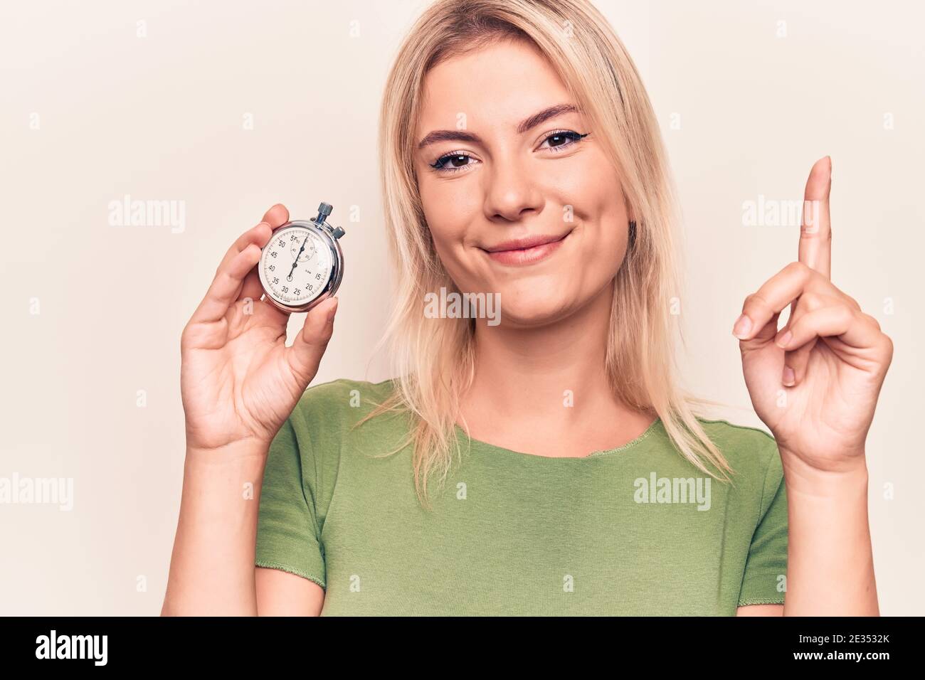 Young beautiful blonde woman doing countdown using stopwatch over white ...