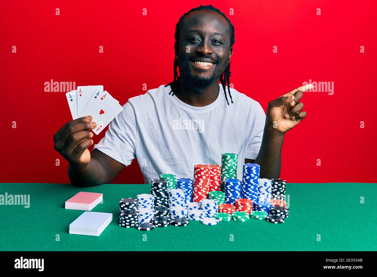 Handsome young black man playing poker holding cards smiling happy ...