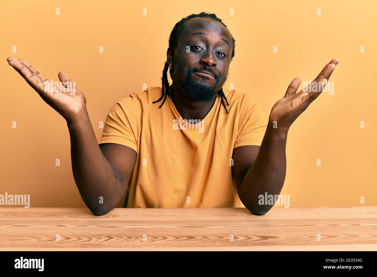 Handsome young black man wearing casual clothes sitting on the table ...