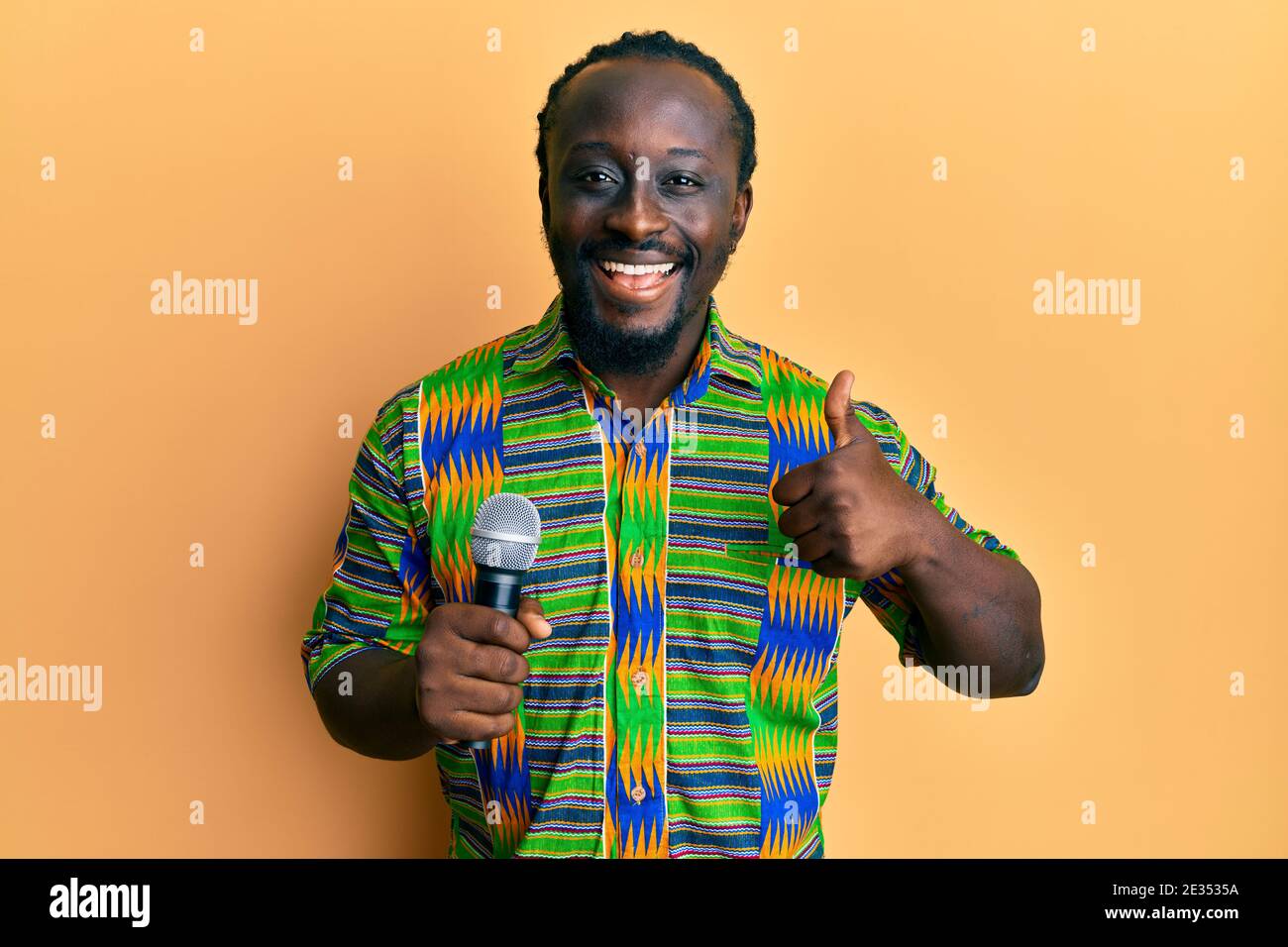 Handsome young black man singing song using microphone smiling happy ...