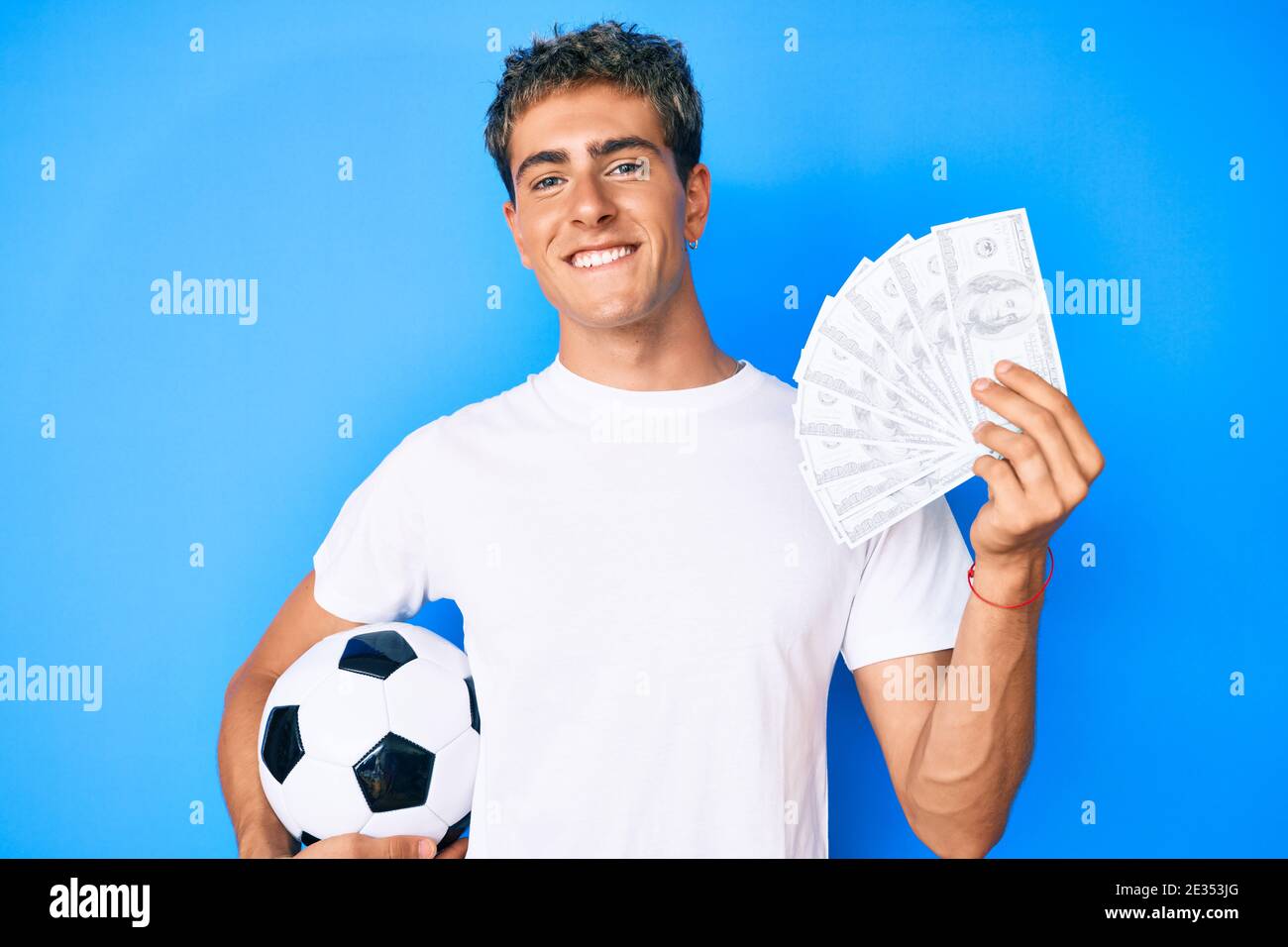 Young handsome man holding soccer ball and dollars banknotes smiling ...