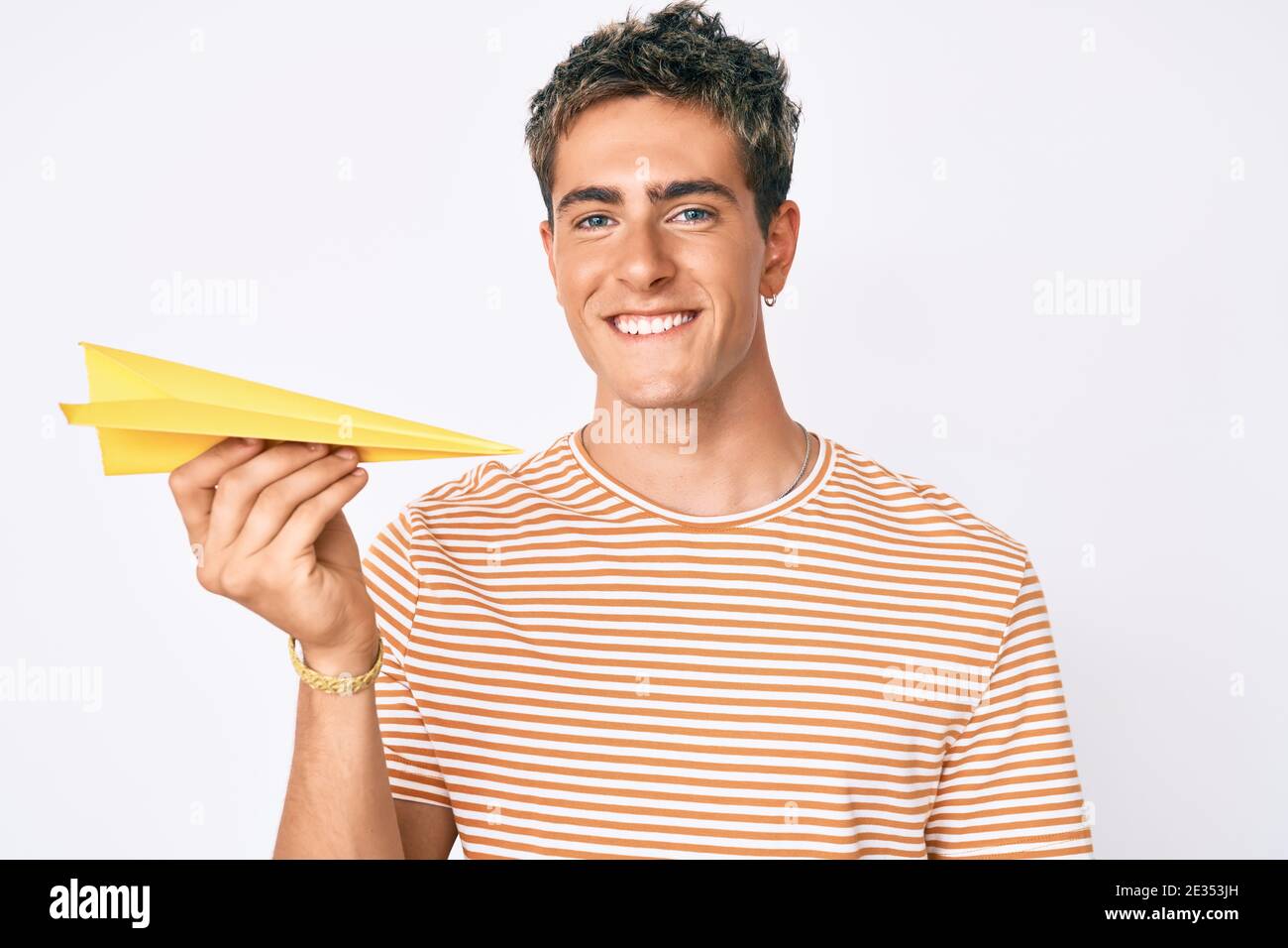 Young handsome man holding paper airplane looking positive and happy ...