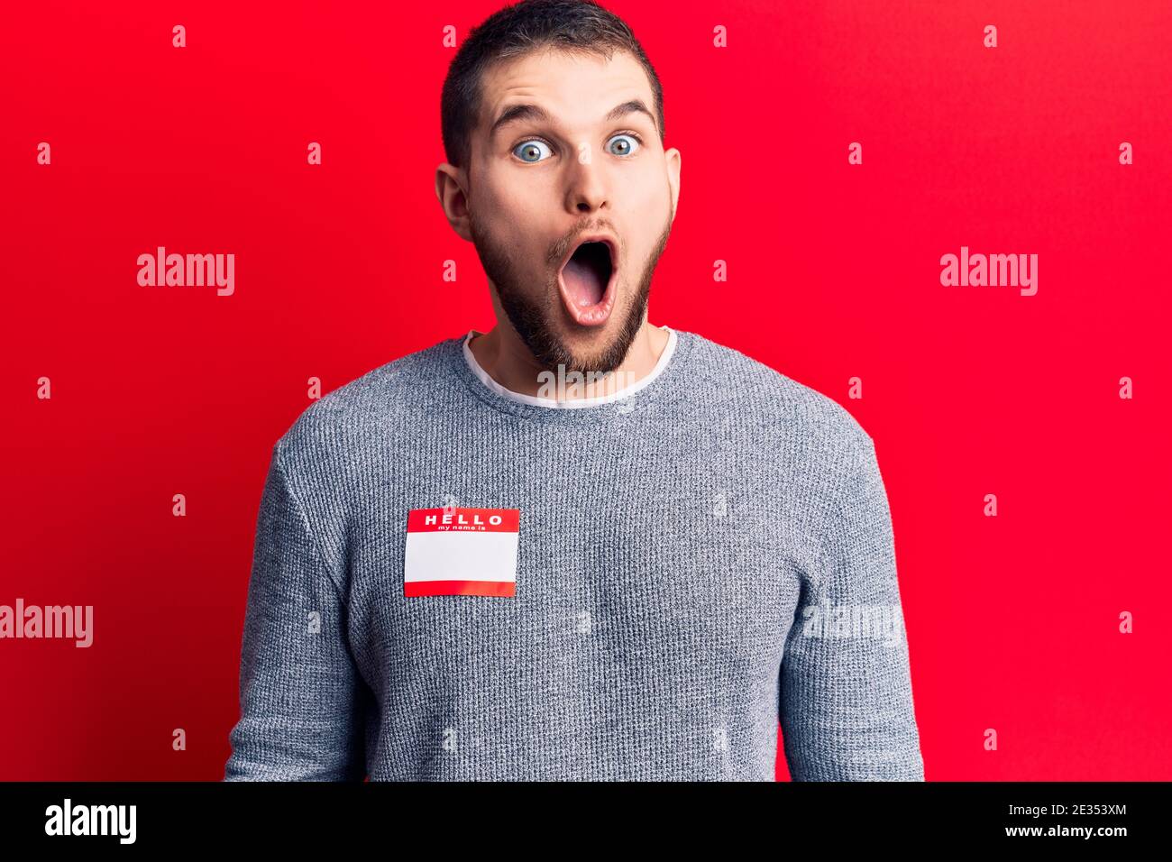 Young handsome man wearing hello my name is sticker scared and amazed ...