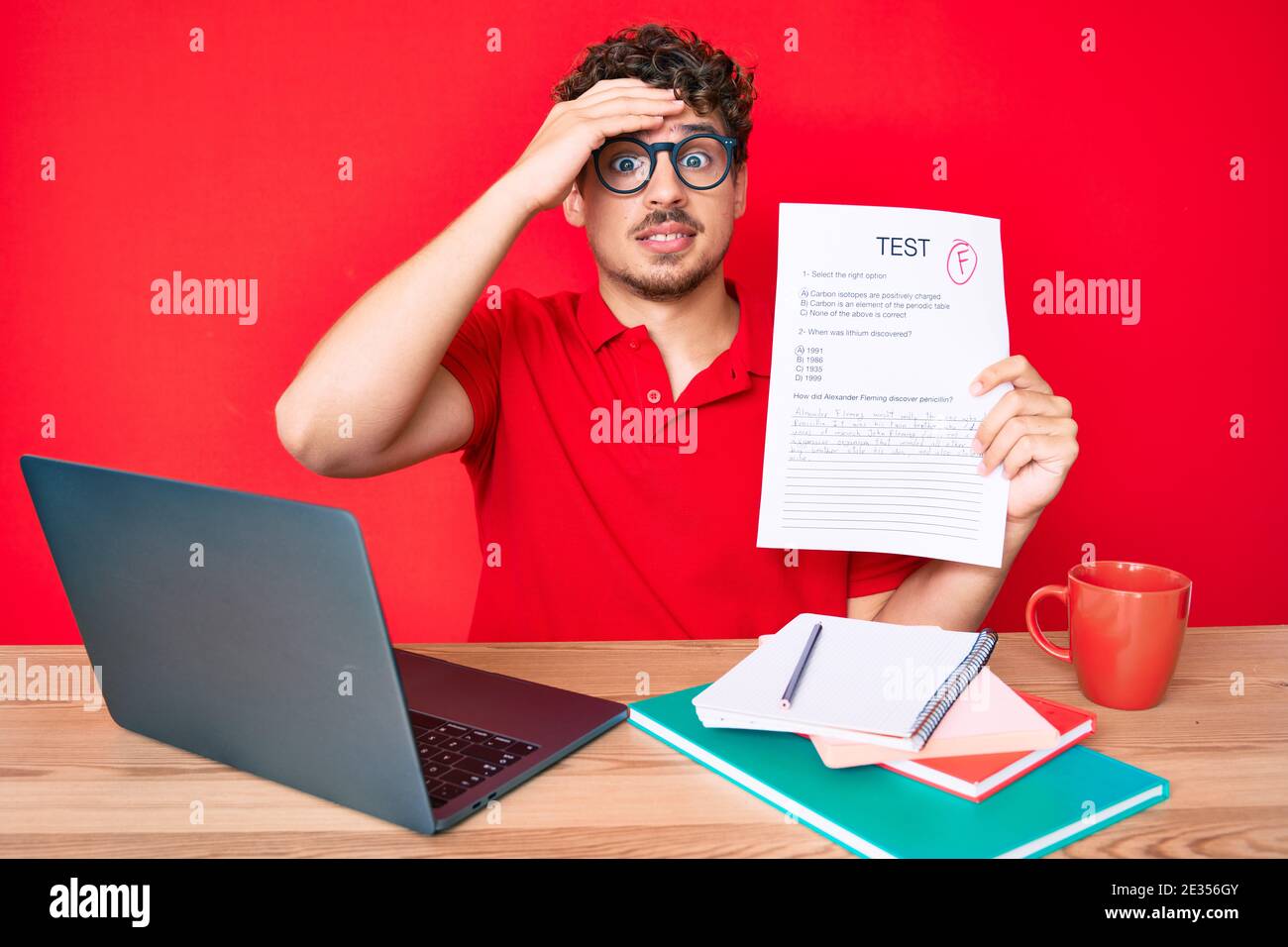 Young caucasian man with curly hair sitting on the table showing failed ...