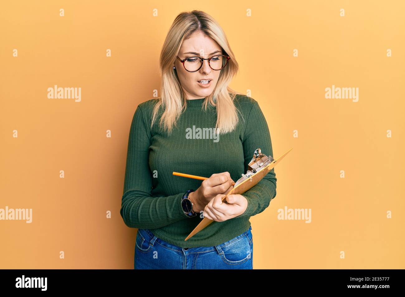 Young caucasian woman writing on checklist clipboard in shock face ...