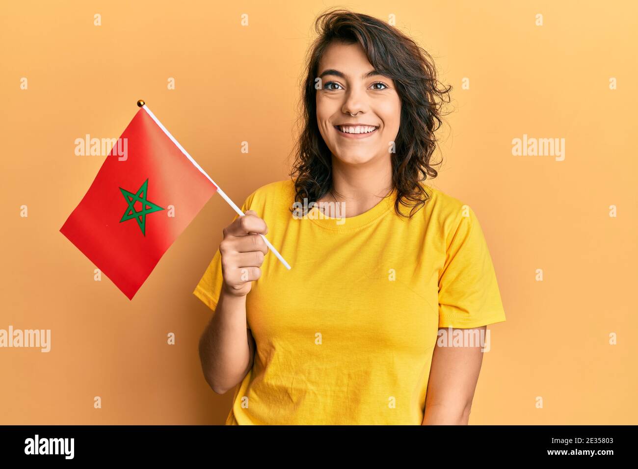 Young hispanic woman holding somalia flag looking positive and happy ...