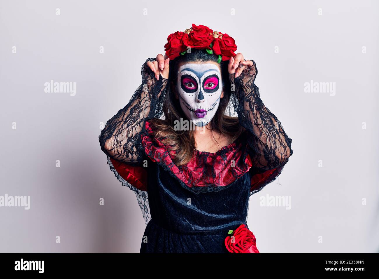 Young woman wearing day of the dead costume over white doing funny ...