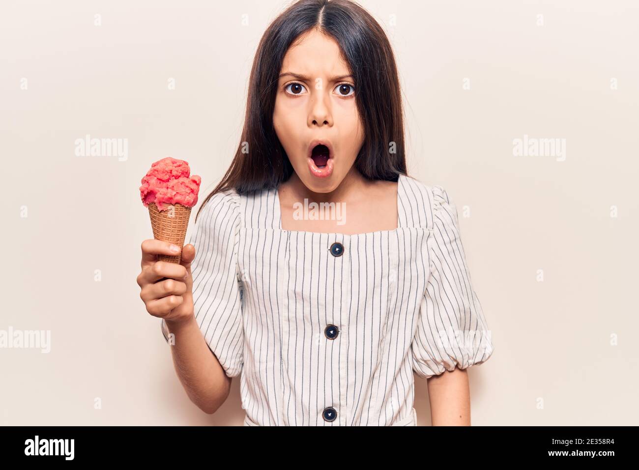 Beautiful child girl holding ice cream scared and amazed with open ...