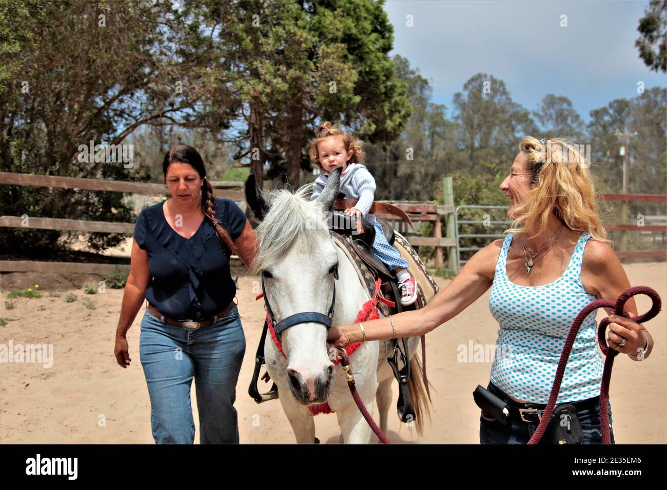 2 year old girl gets her first ride on a horse, with the aid of the ...