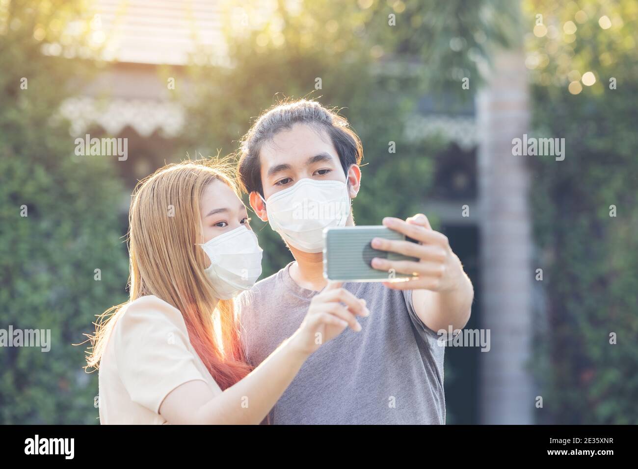 Asis couple In Medical Masks Making Selfie With Phone Stock Photo - Alamy