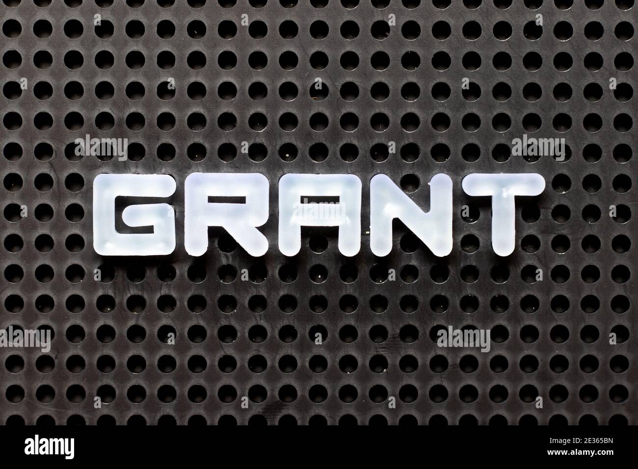 White color alphabet with word grant on black pegboard background Stock ...