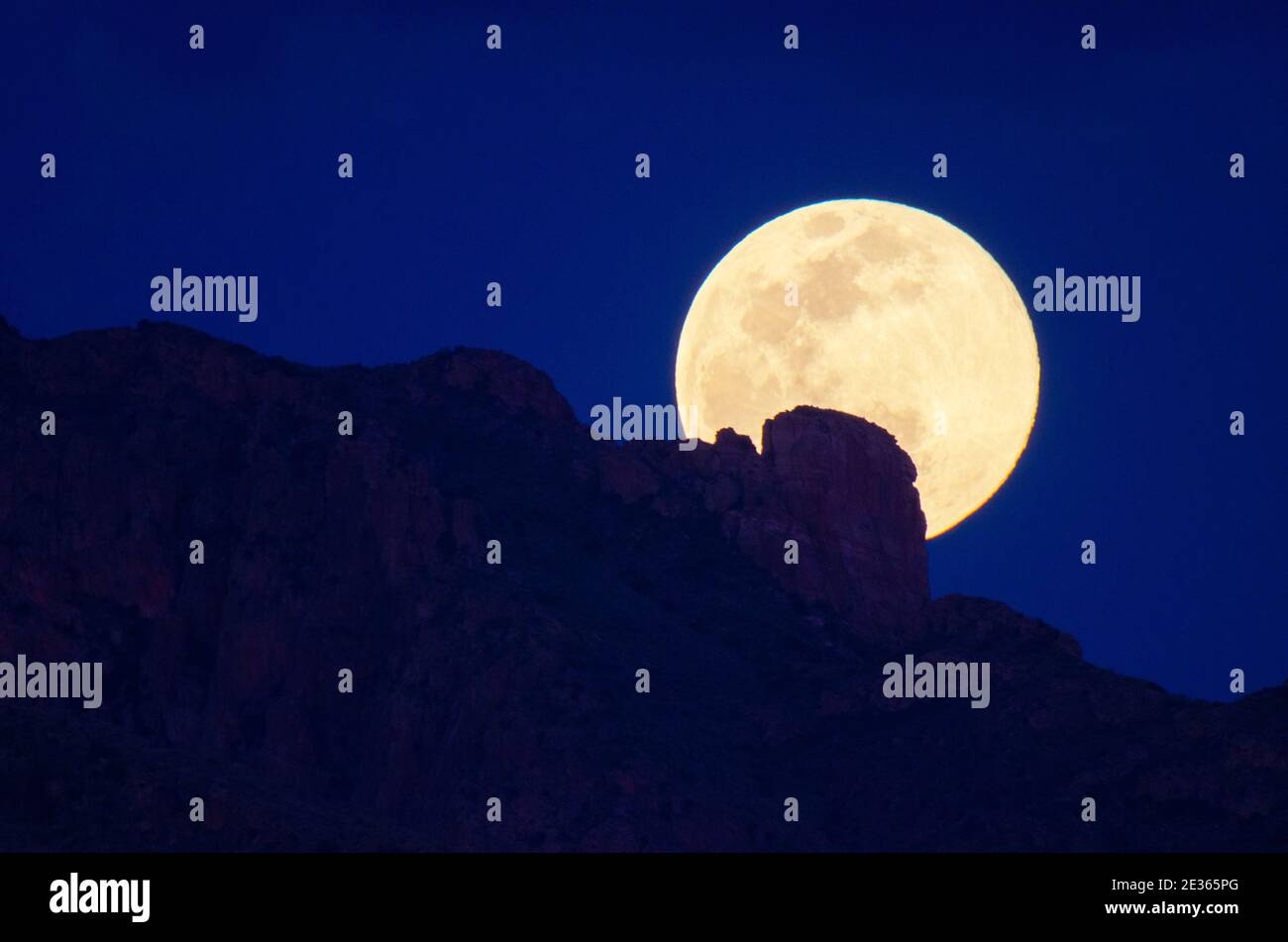 Full moon rising over desert mountains Stock Photo - Alamy