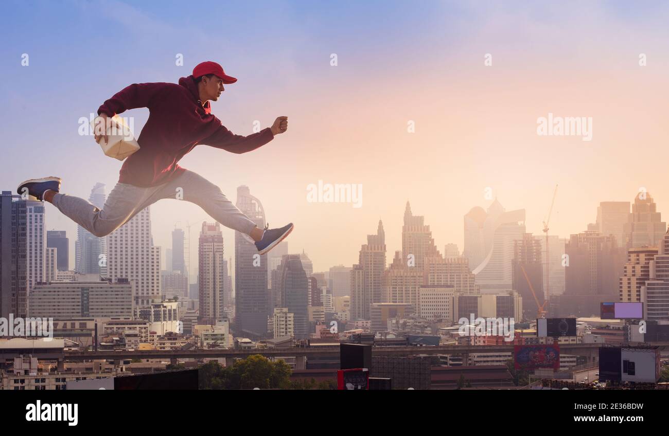 Delivery man holding cardboard boxes and jumping high on city ...