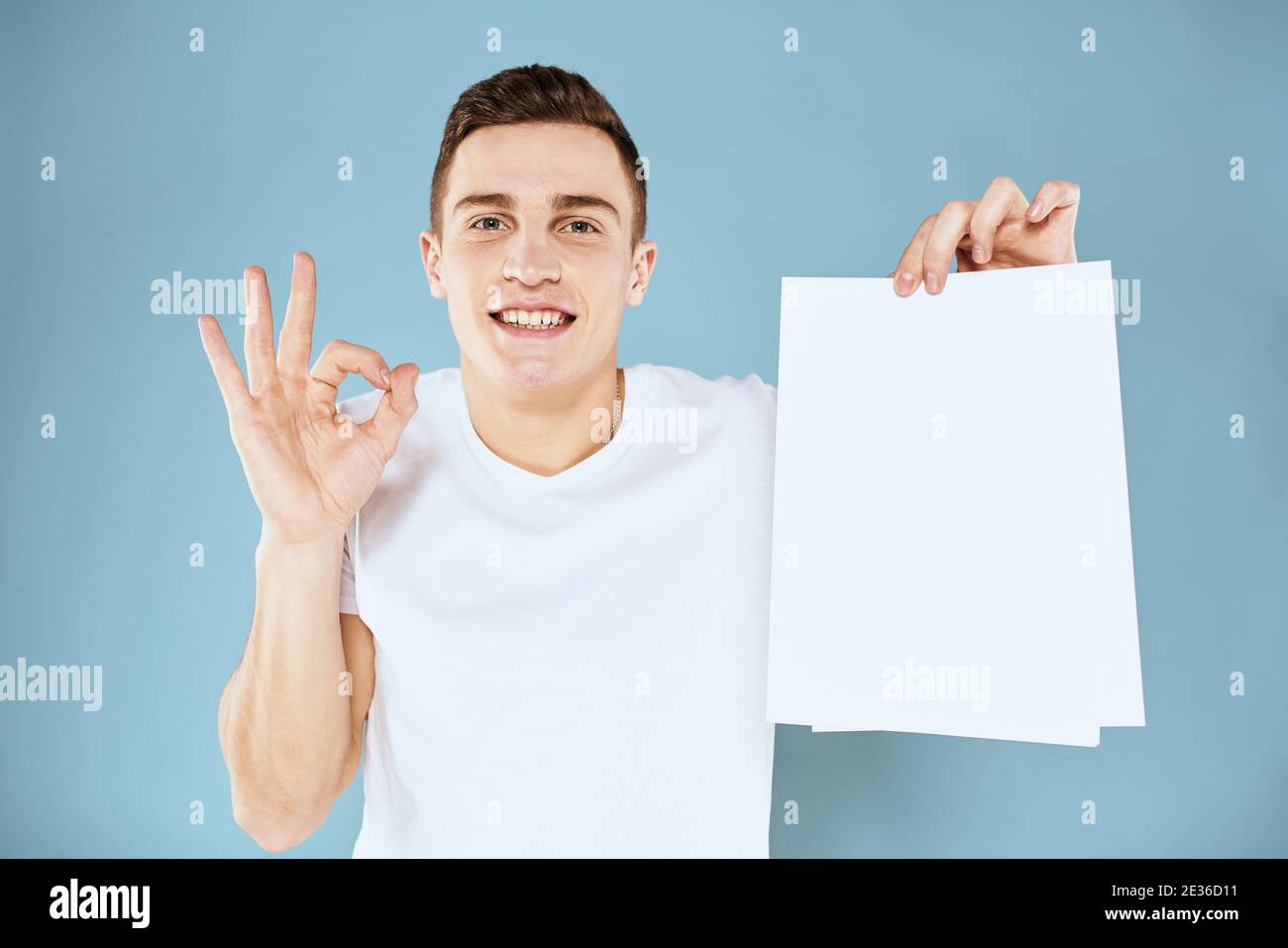 man holding a sheet of paper in his hands white t-shirt cropped view ...