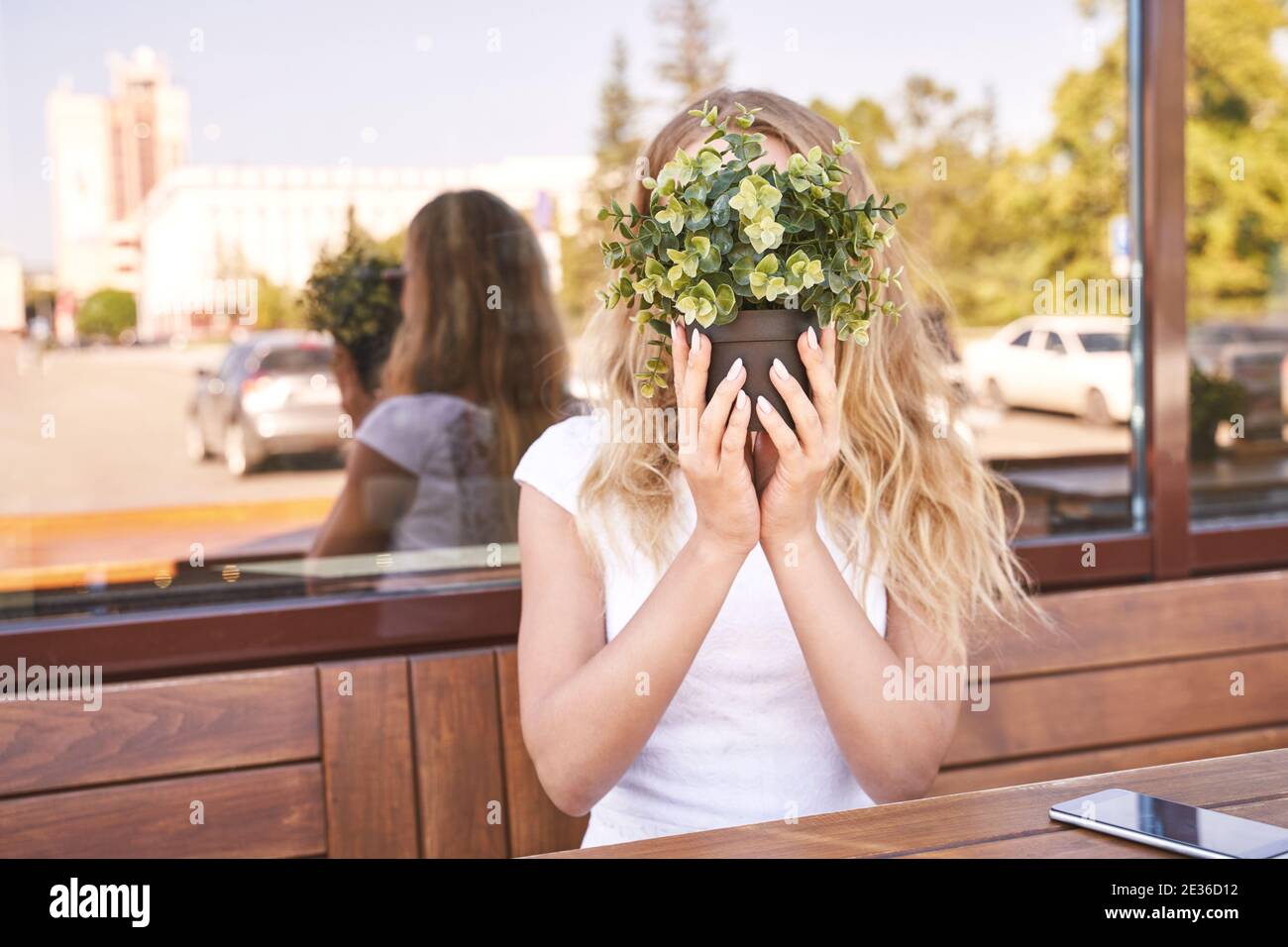 Pretty young woman hide face by green. Outdoors anonymity portrait ...