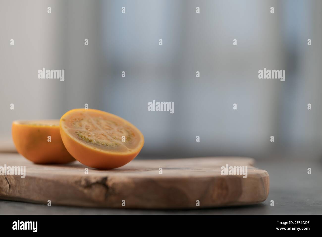 Lulo fruit sliced in halves on olive wood board on kitchen countertop ...