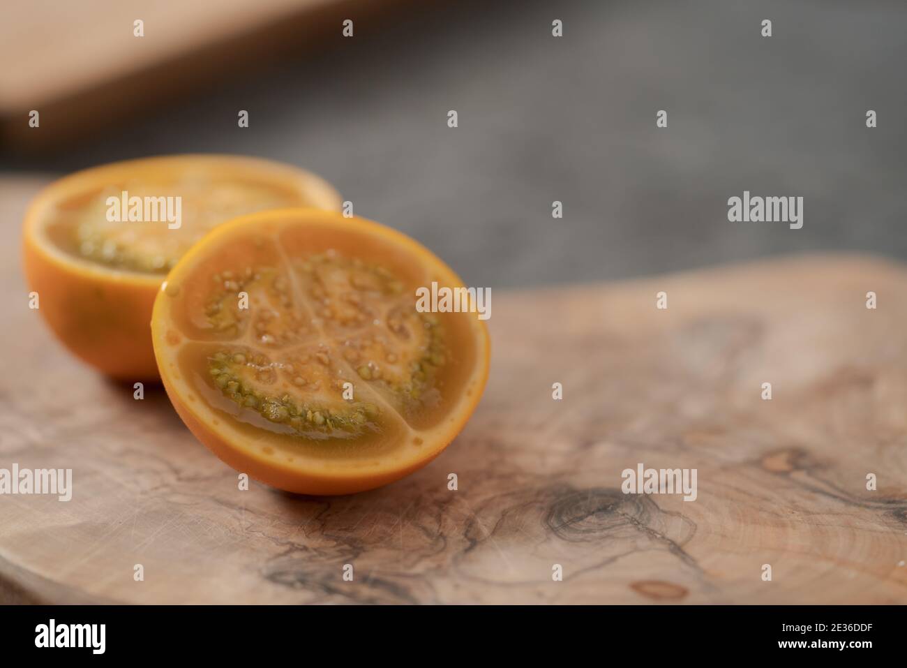 Lulo fruit sliced in halves on olive wood board on kitchen countertop ...