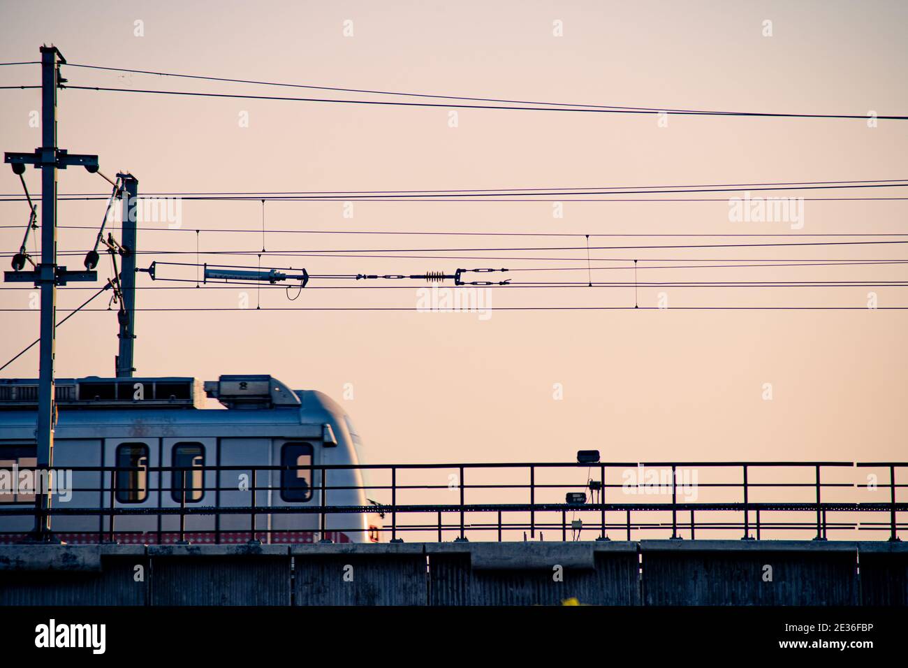 Aerial dusk shots of metro train on elevated bridge with people visible ...