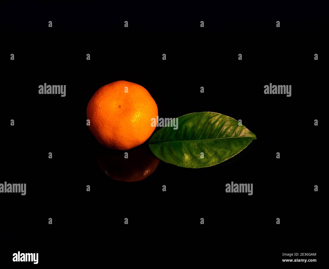 Orange tangerine fruit with green leaf on a black background. Orange ...