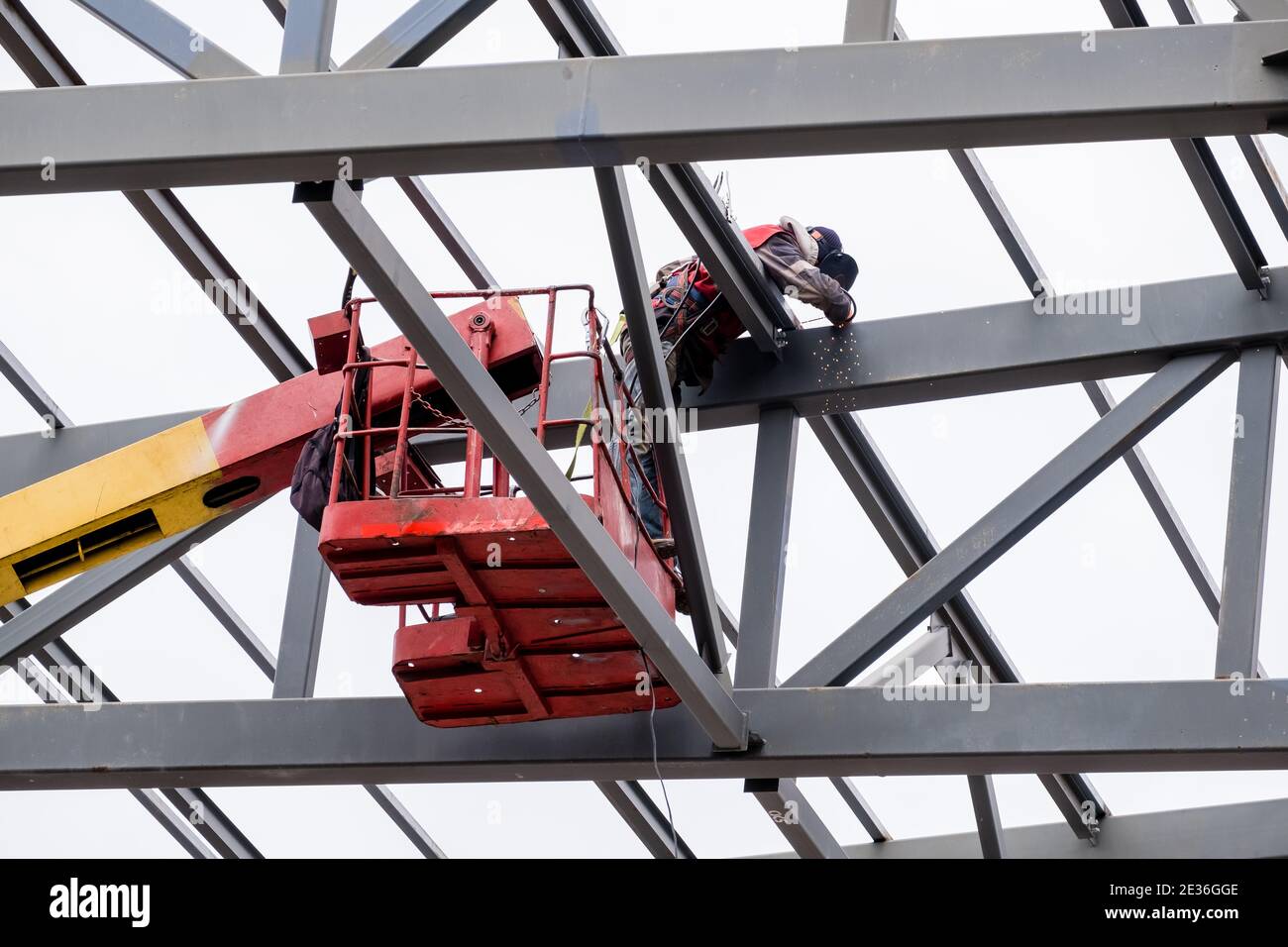 Man worker on a crane performs high-rise work on welding metal ...