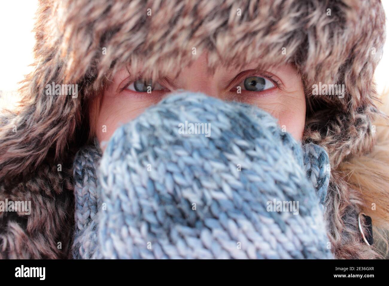 Portrait of a young woman in a fur cap with covered face outdoor. Close ...