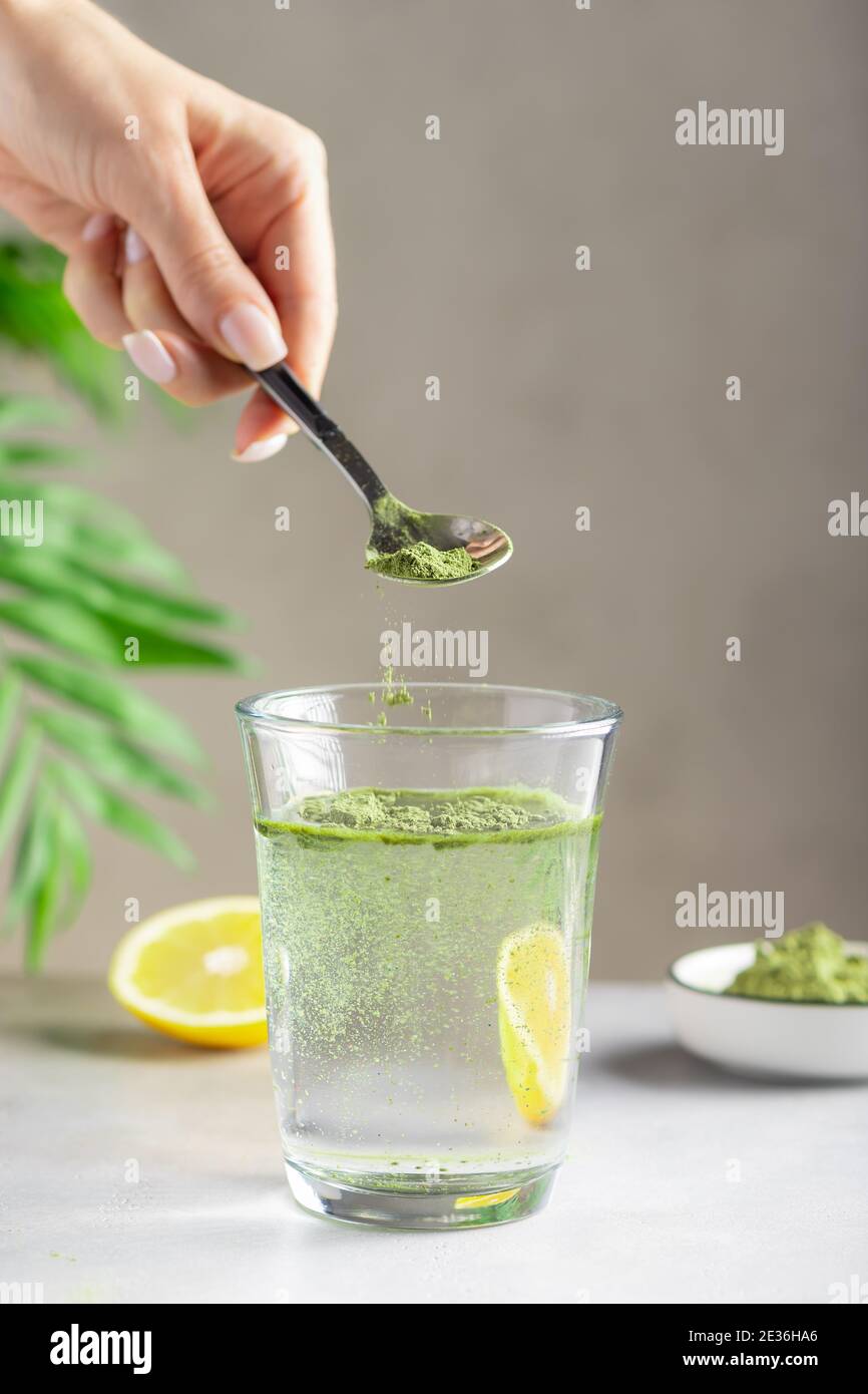 female hand pouring green superfood powder into glass of water Stock ...