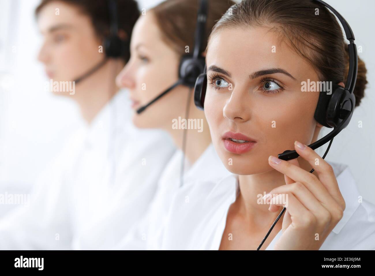 Call center. Beautiful young woman using headset and computer to help ...