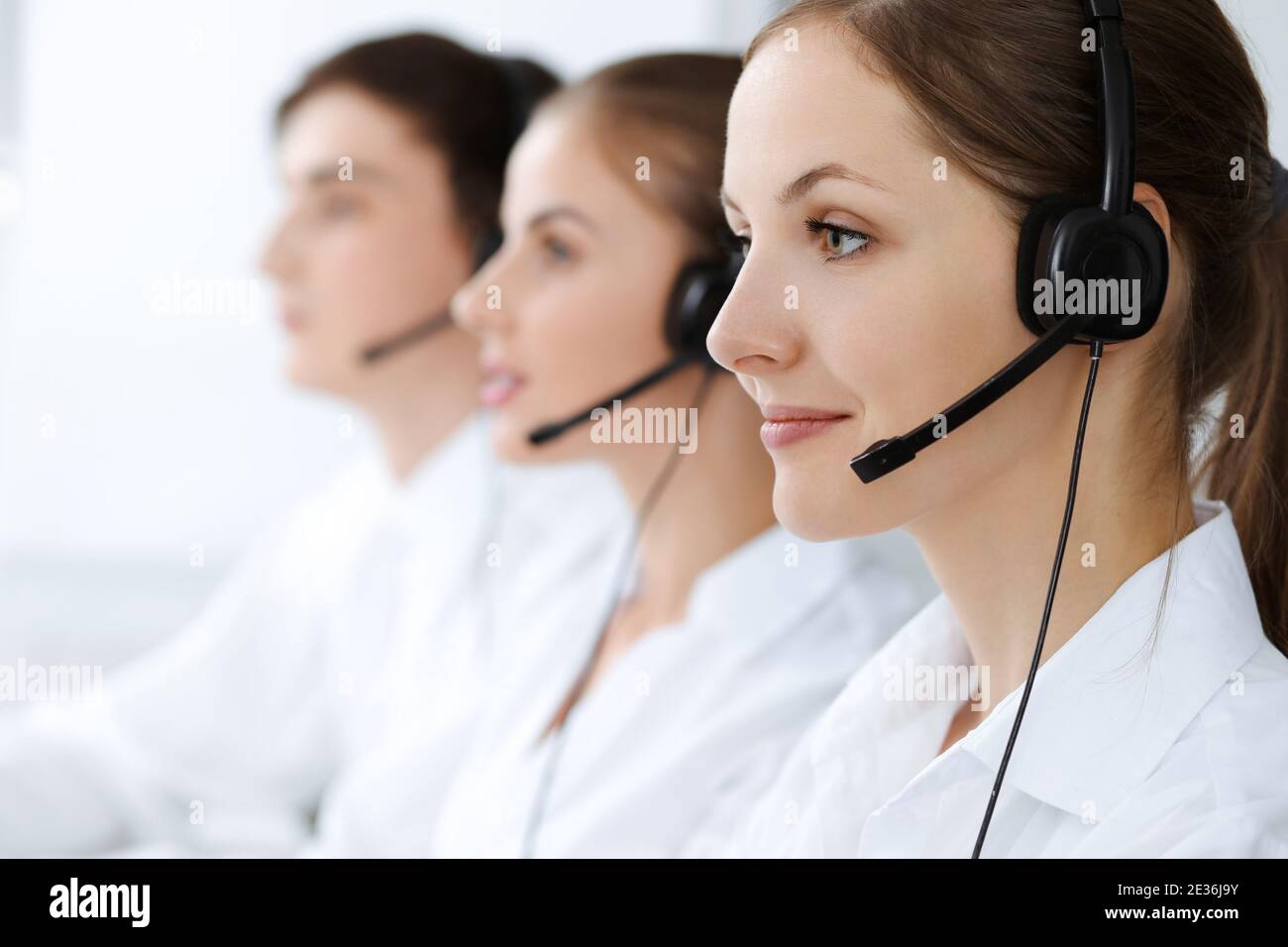 Call center. Beautiful young woman using headset and computer to help ...