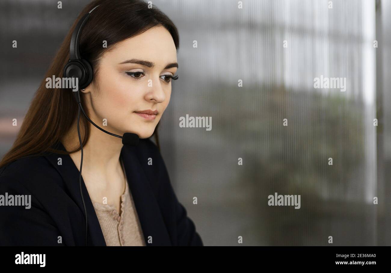 Two young people in headsets are smiling and talking to the clients ...