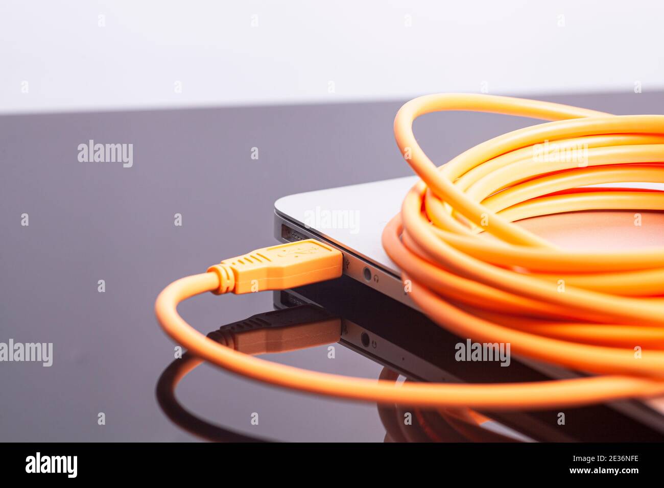 laptop with orange rolled cable Stock Photo - Alamy